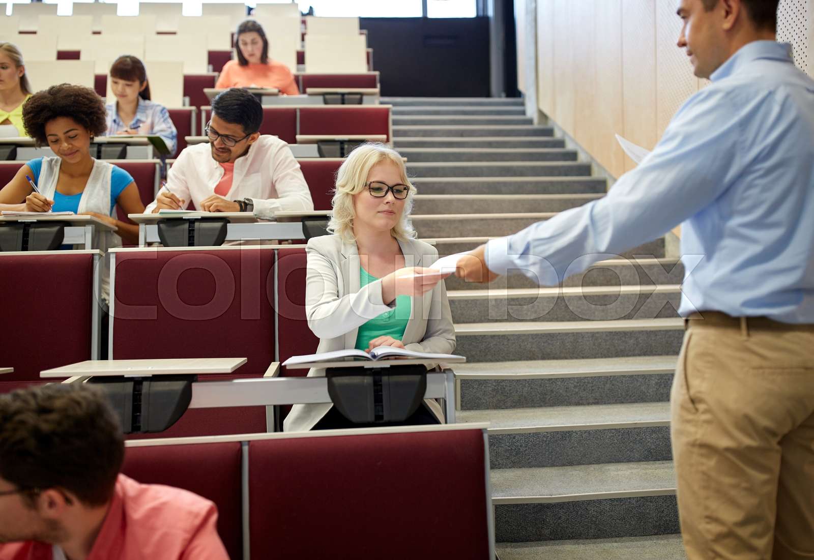 teacher giving exam tests to students at lecture | Stock image | Colourbox