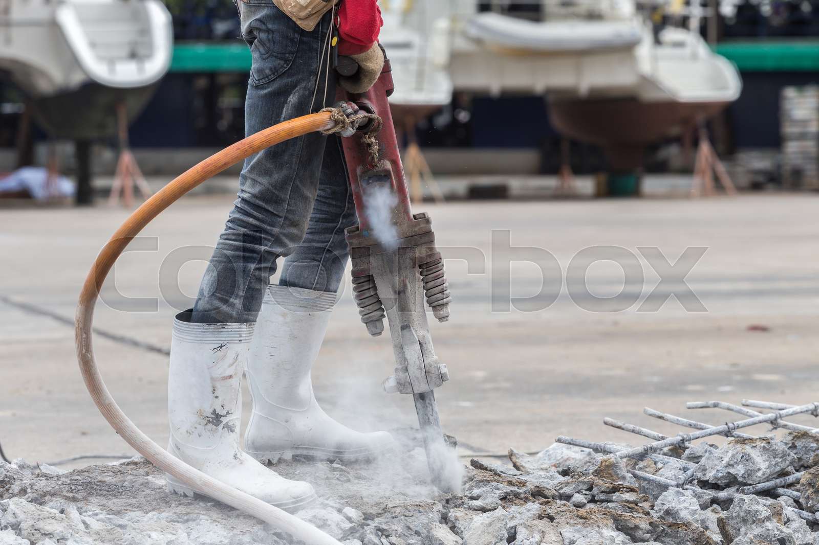 Construction worker removes excess concrete with drilling machine ...
