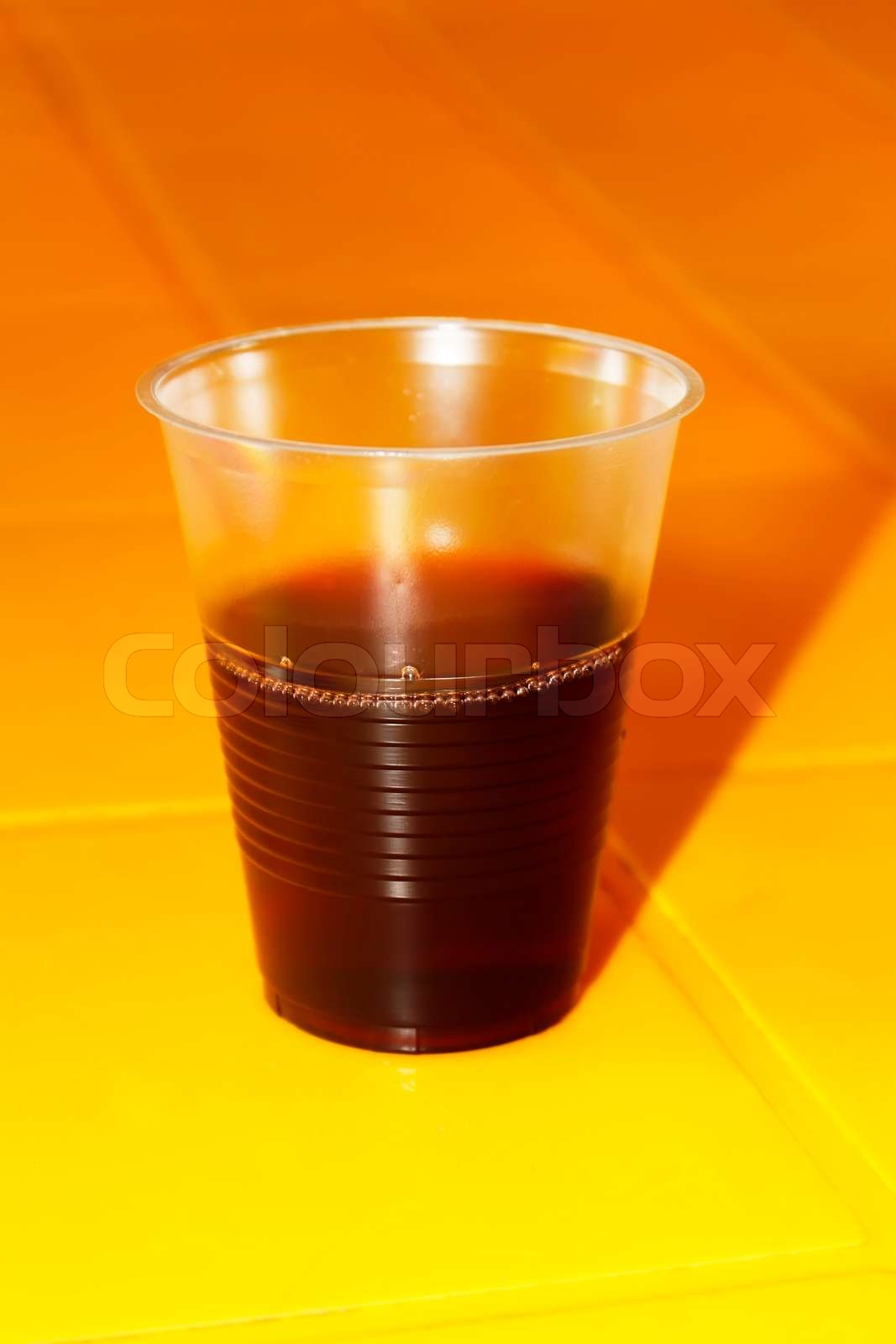 Plastic cup with dark red juice on bright yellow surface | Stock image ...