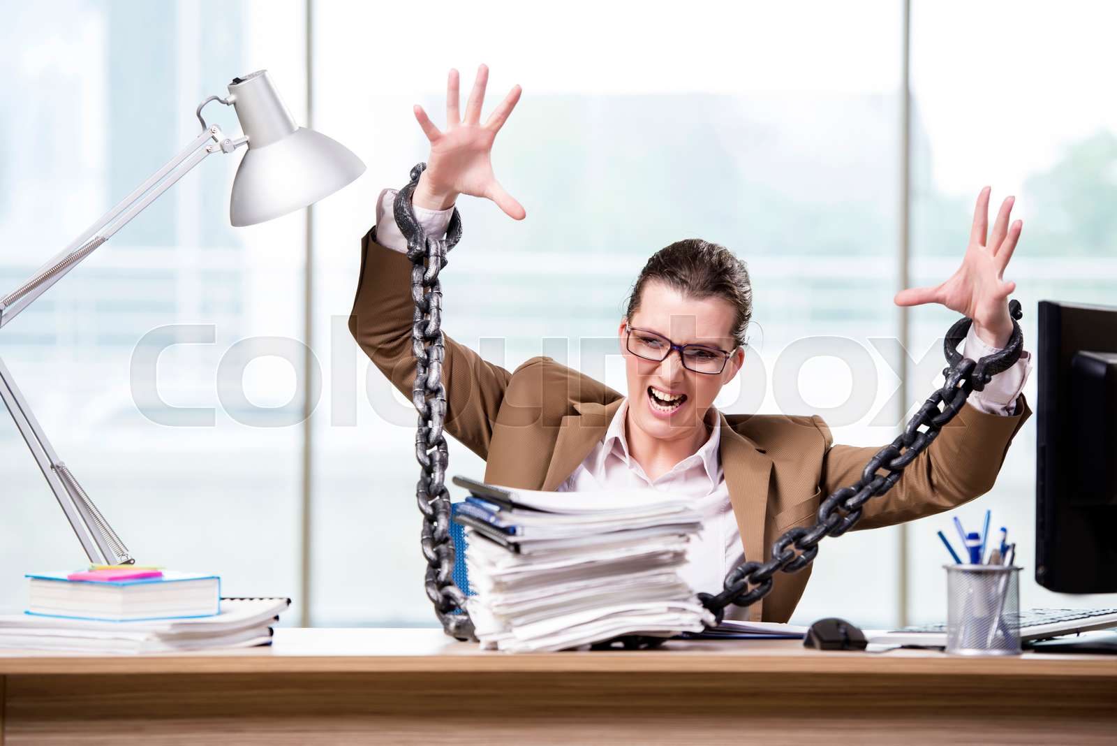 Woman chained to her working desk | Stock image | Colourbox