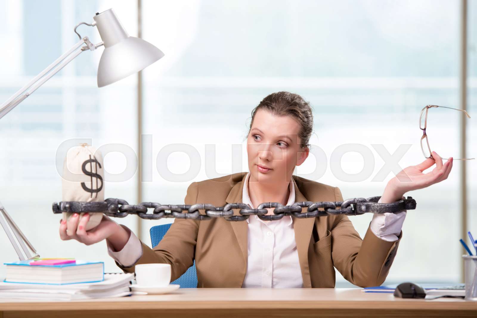 Woman chained to her working desk | Stock image | Colourbox