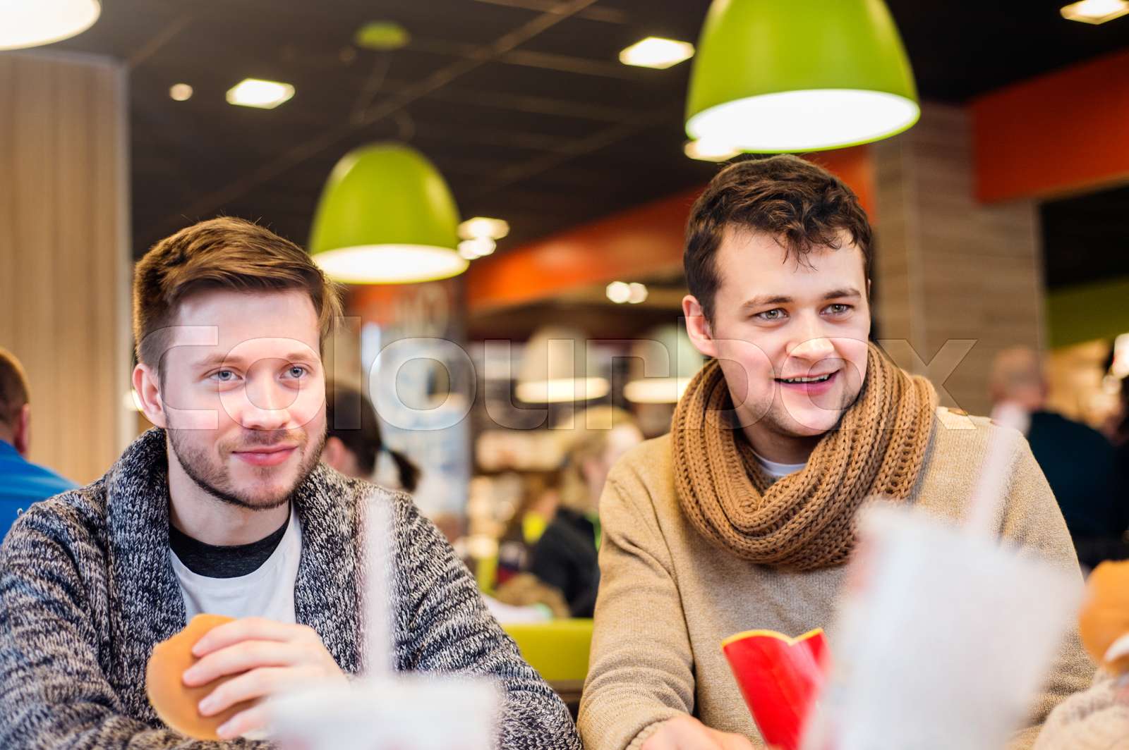 Two men eating out in fast food restaurant, talking | Stock image ...