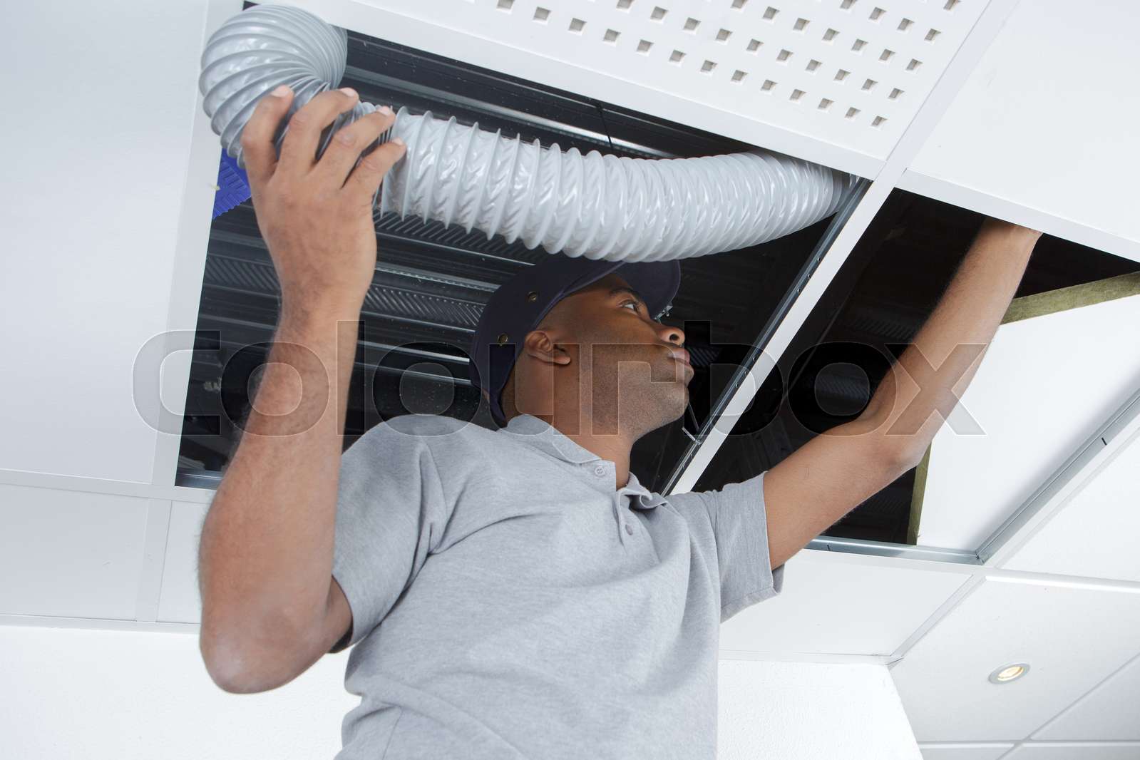 Man fitting ventilation hose into roofspace | Stock image | Colourbox