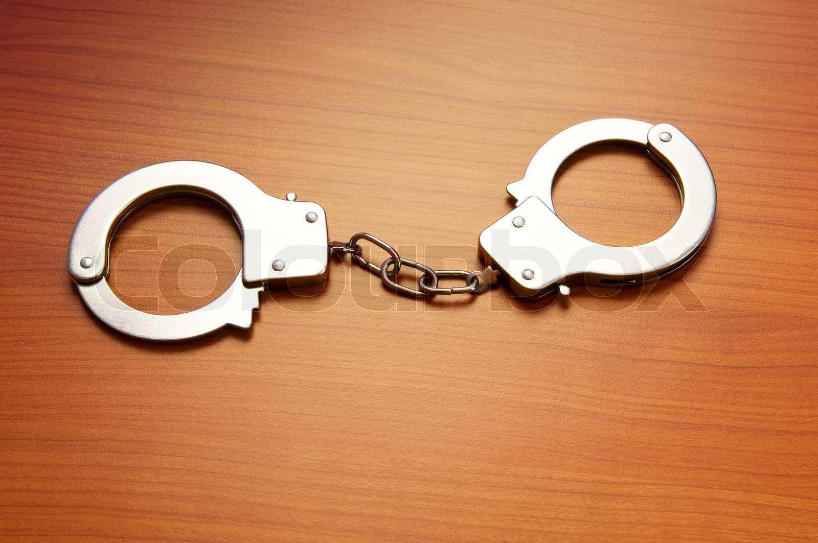 Metall-Handschellen auf dem hölzernen Hintergrund | Stock Bild | Colourbox
