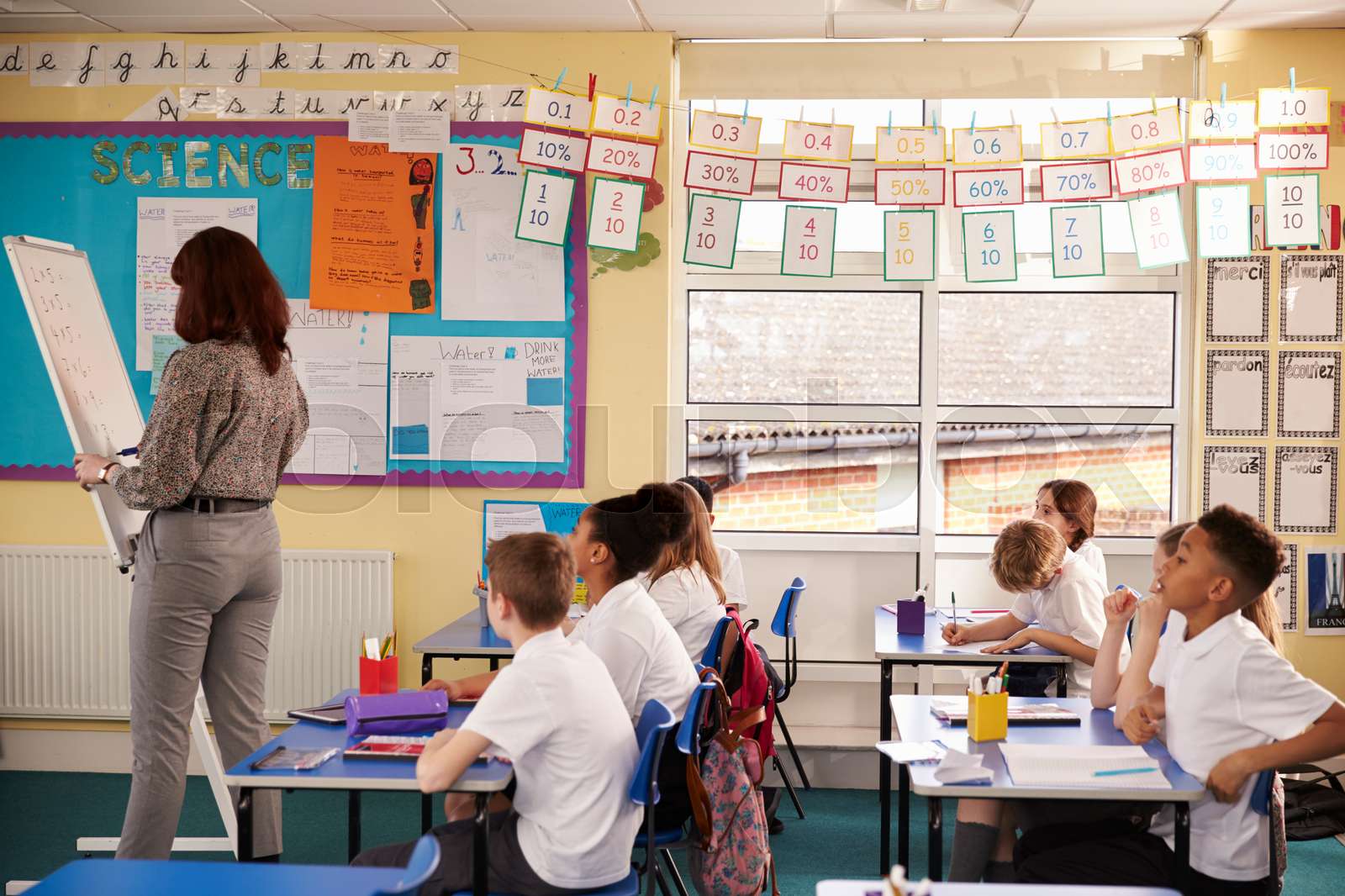 Primary school teacher writing on a flip chart in a lesson | Stock ...