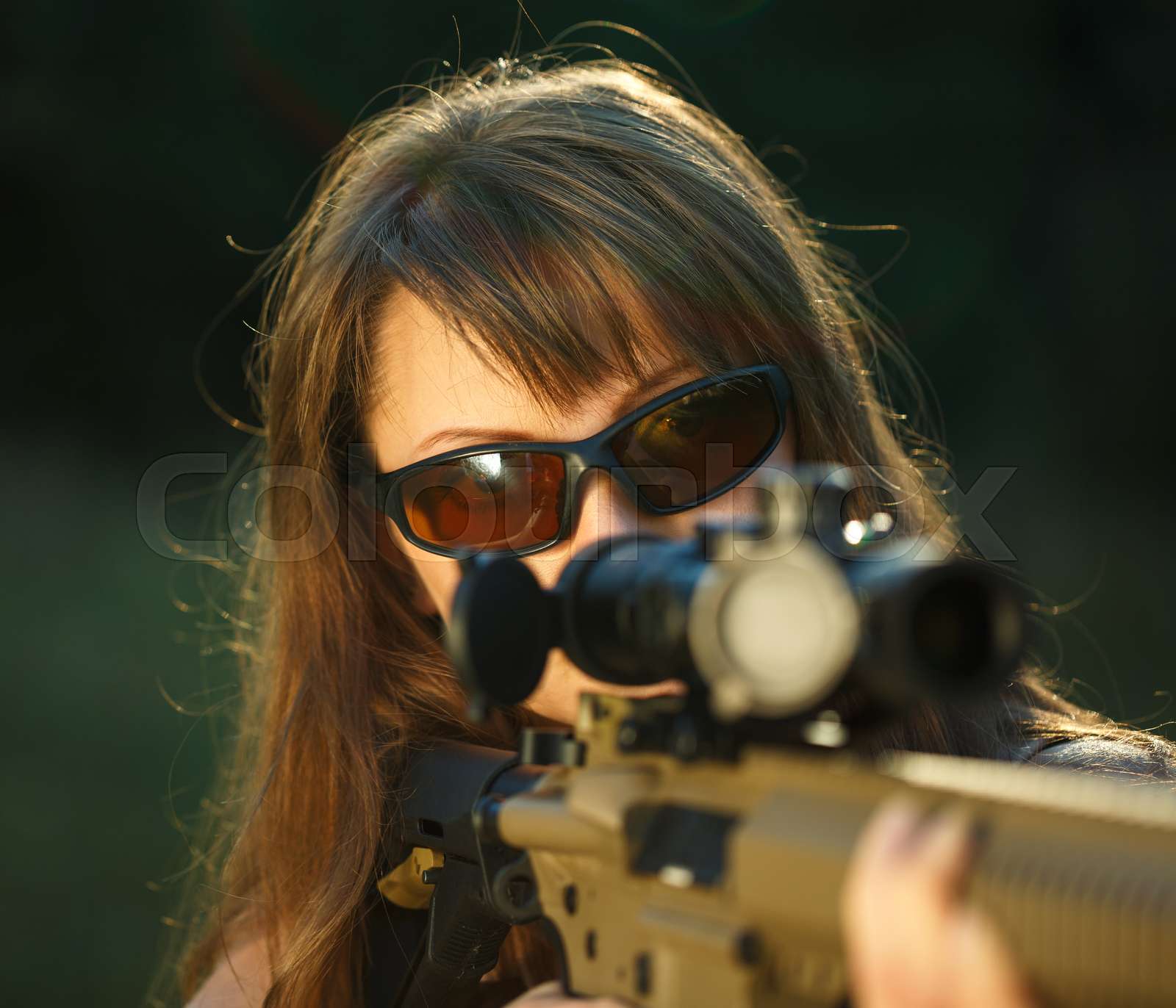 Girl with a gun for trap shooting and shooting glasses aiming at a ...