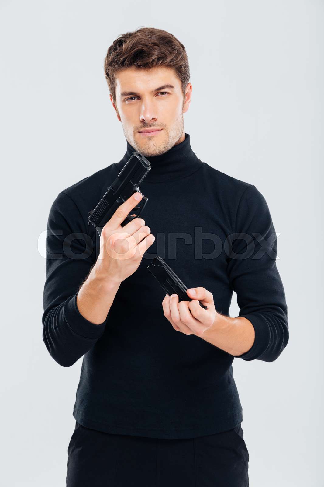 Serious young man standing and loading a gun | Stock image | Colourbox
