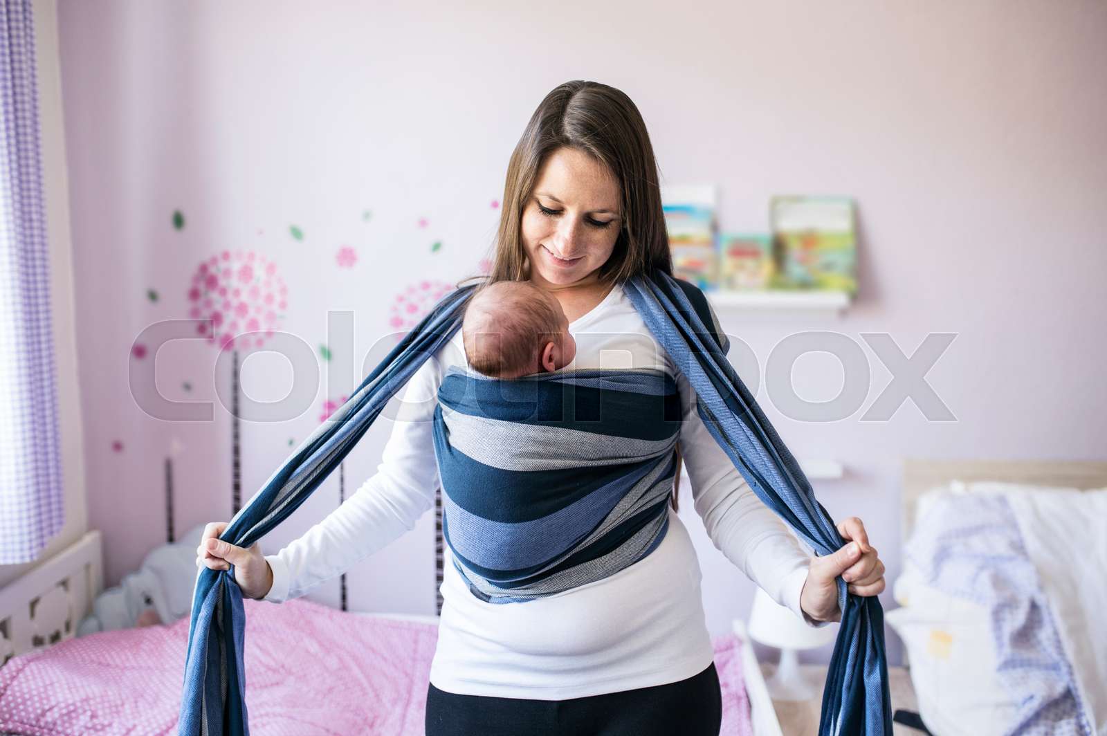 Beautiful young mother wrapping her son into sling | Stock image ...