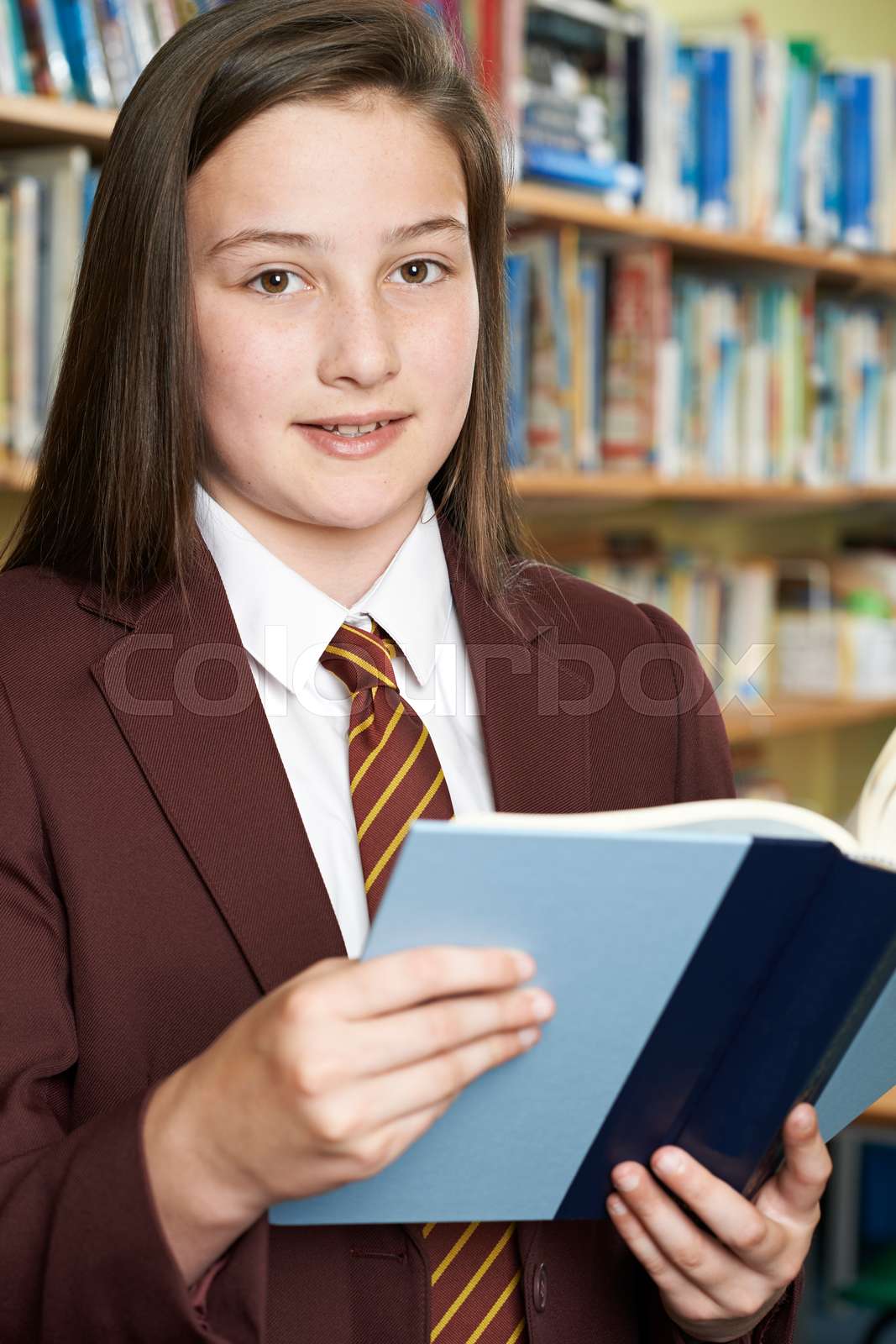 Girl Wearing School Uniform Reading Book In Library | Stock image ...