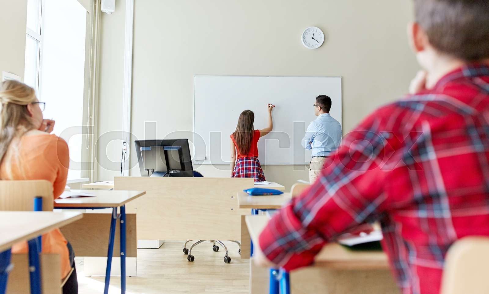 teacher and student writing on board at school | Stock image | Colourbox