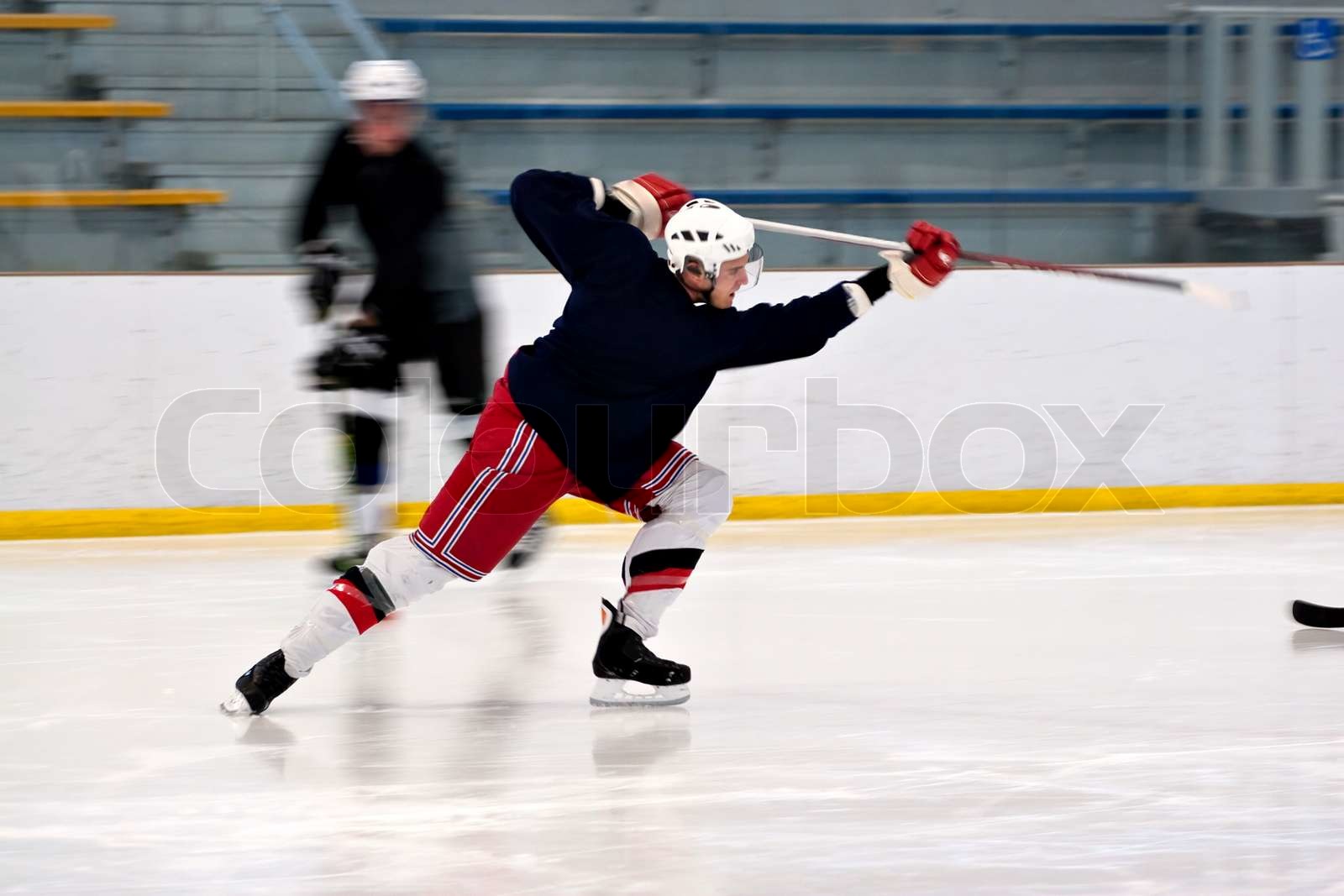 A hockey player shooting the puck as he speeds down the ice. Slight ...