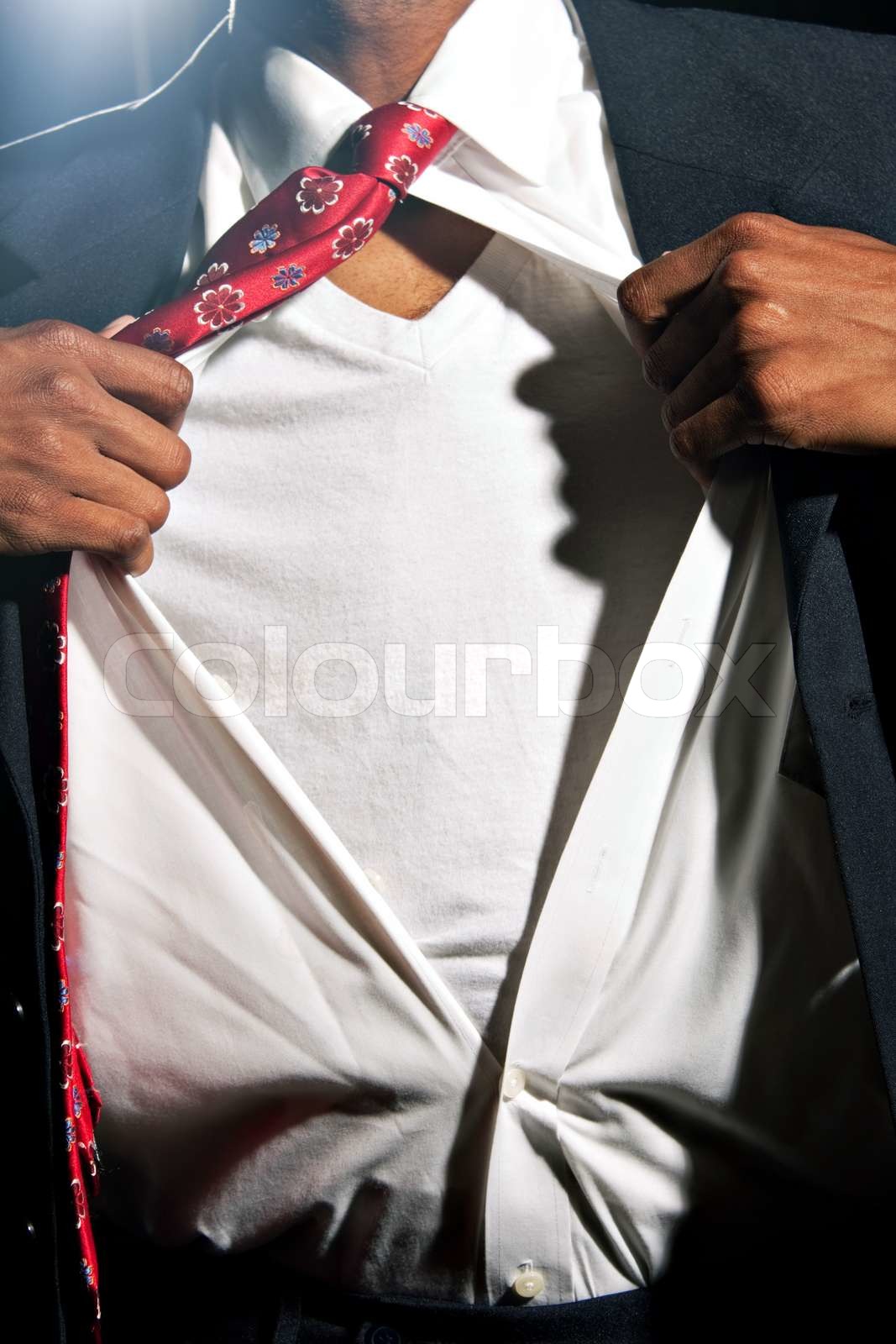 A young African American business man ripping his shirt open to reveal ...