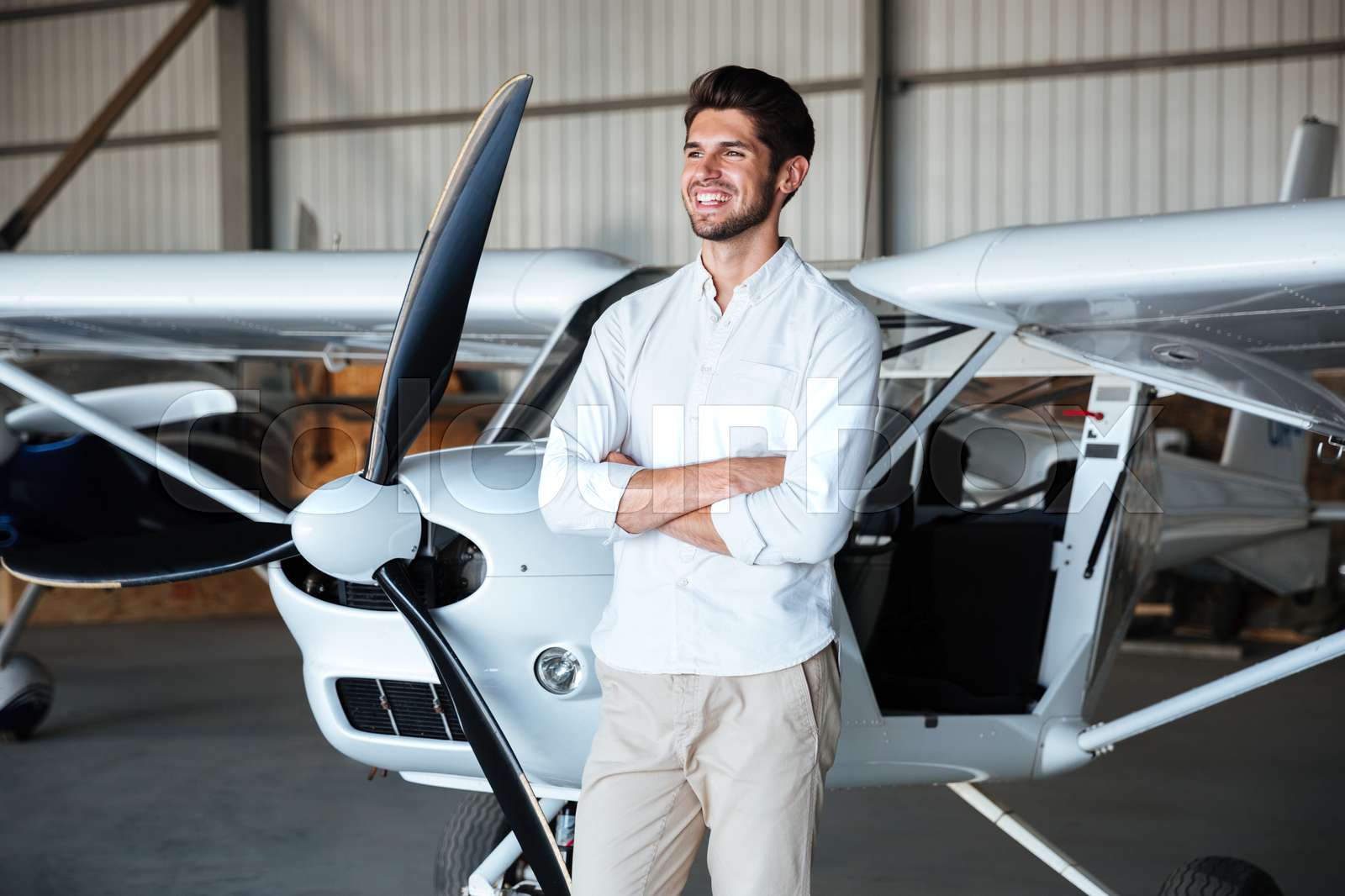 Cheerful young man standing near the plane | Stock image | Colourbox