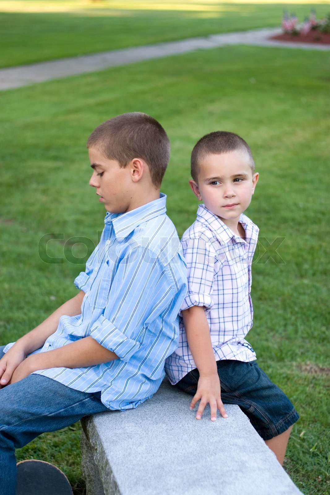 Two brothers sitting back to back on a bench in the park. | Stock image ...