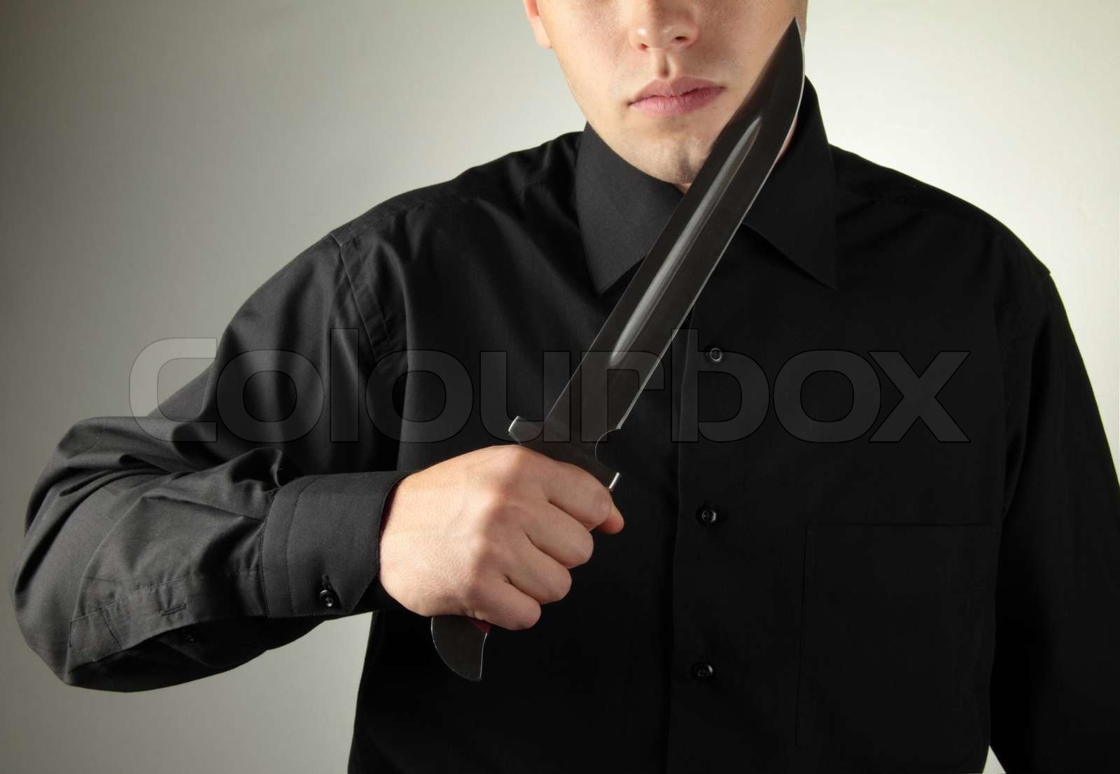 standing man in black with knife concept | Stock image | Colourbox