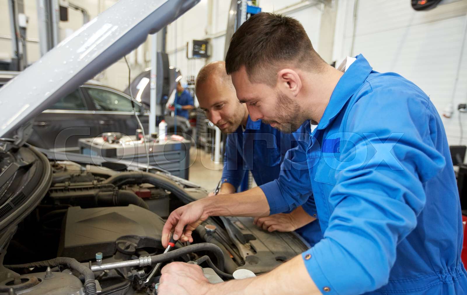 mechanic men with wrench repairing car at workshop | Stock image ...