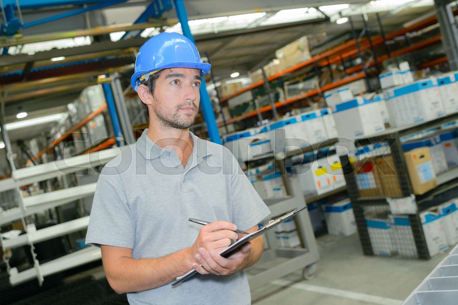 Man in warehouse writing on clipboard | Stock image | Colourbox