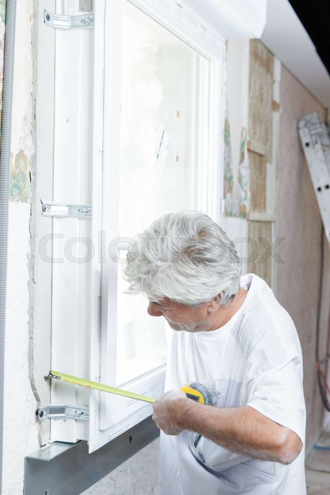 Mason measuring up a window | Stock image | Colourbox
