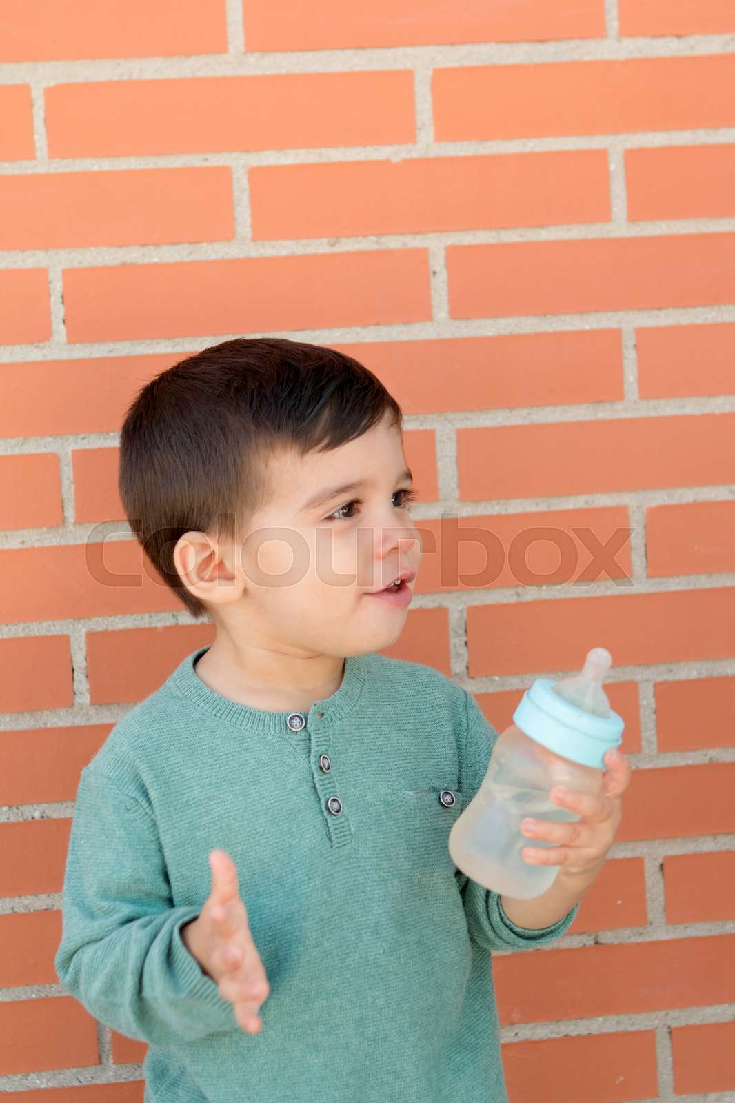Smiling little child taking a bottle | Stock image | Colourbox