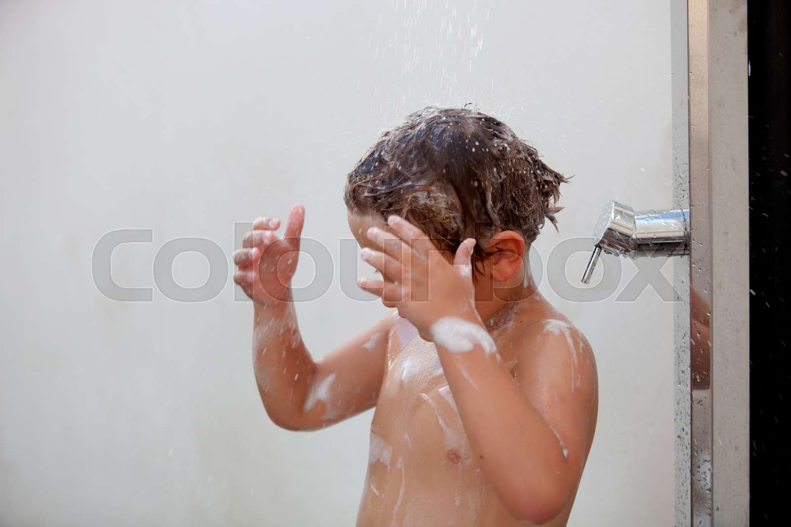Funny kid showering in the yard | Stock image | Colourbox