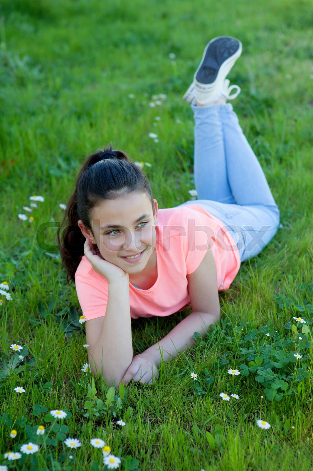 Happy preteen girl lying in the grass | Stock image | Colourbox