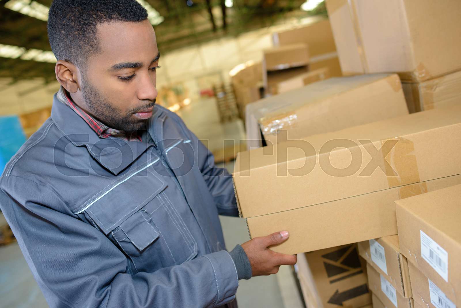 Man selecting boxes in warehouse | Stock image | Colourbox