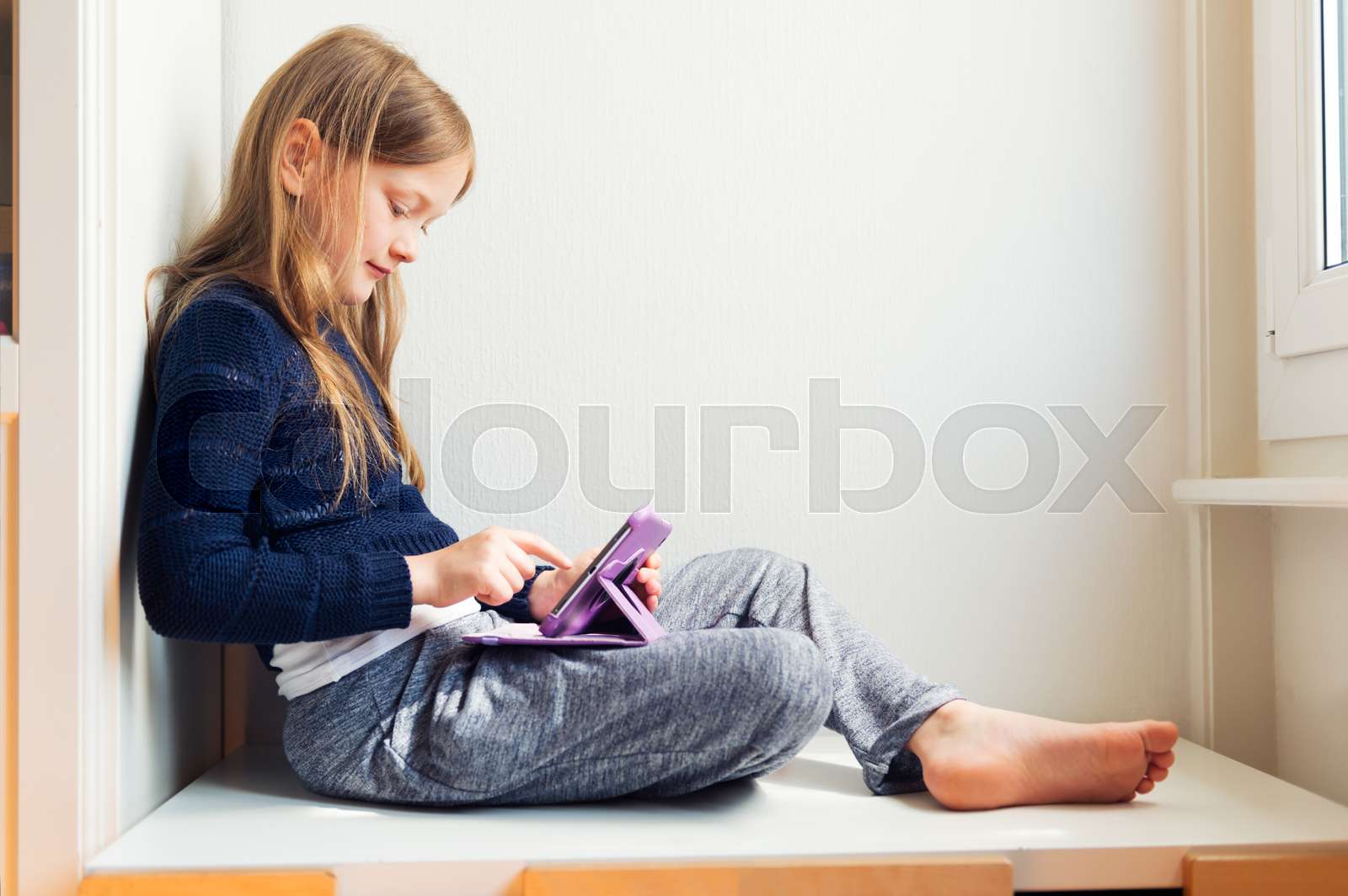 Adorable little girl playing on a digital tablet | Stock image | Colourbox