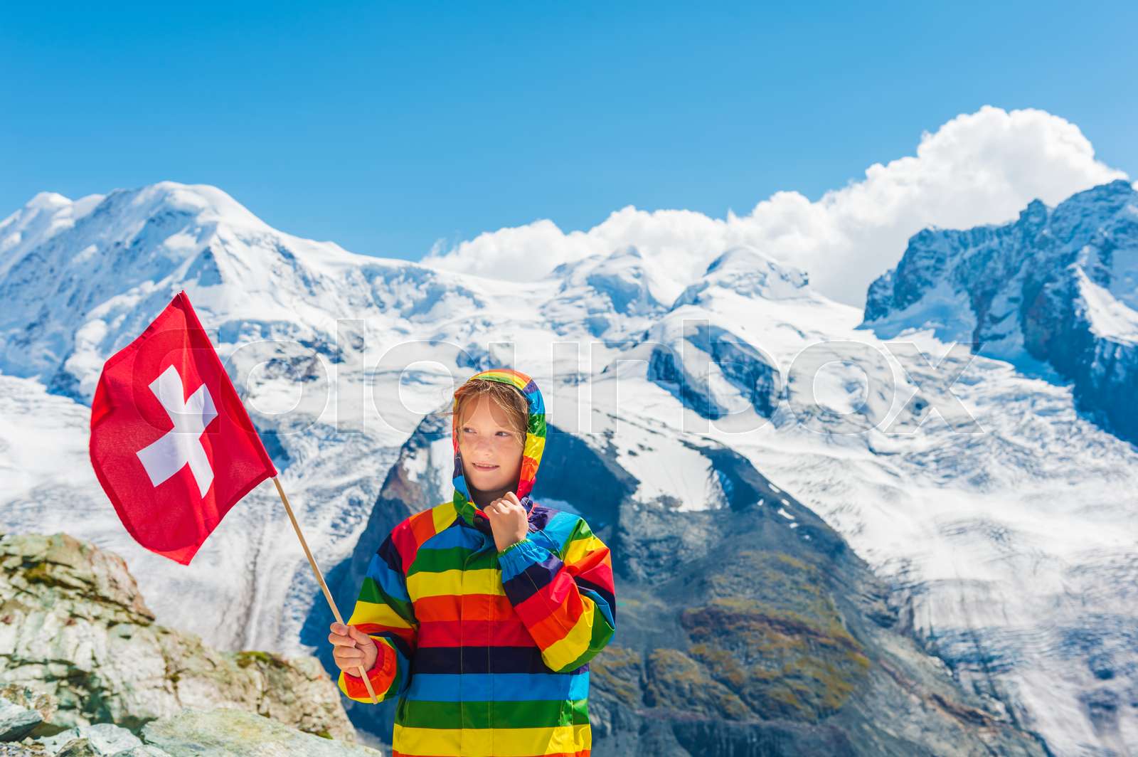Cute little girl wearing bright rainbow colored coat, holding swiss ...