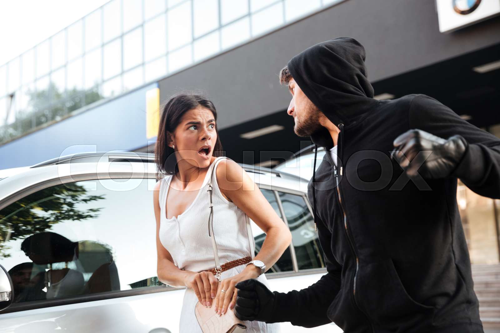 Aggressive young man thief in hoodie robbing scared woman | Stock image ...