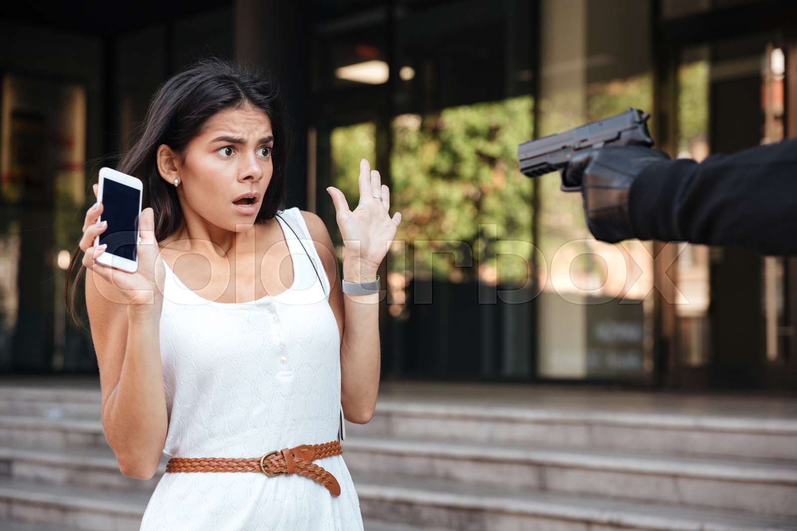 Scared woman holding cell phone threatened by criminal with gun | Stock ...
