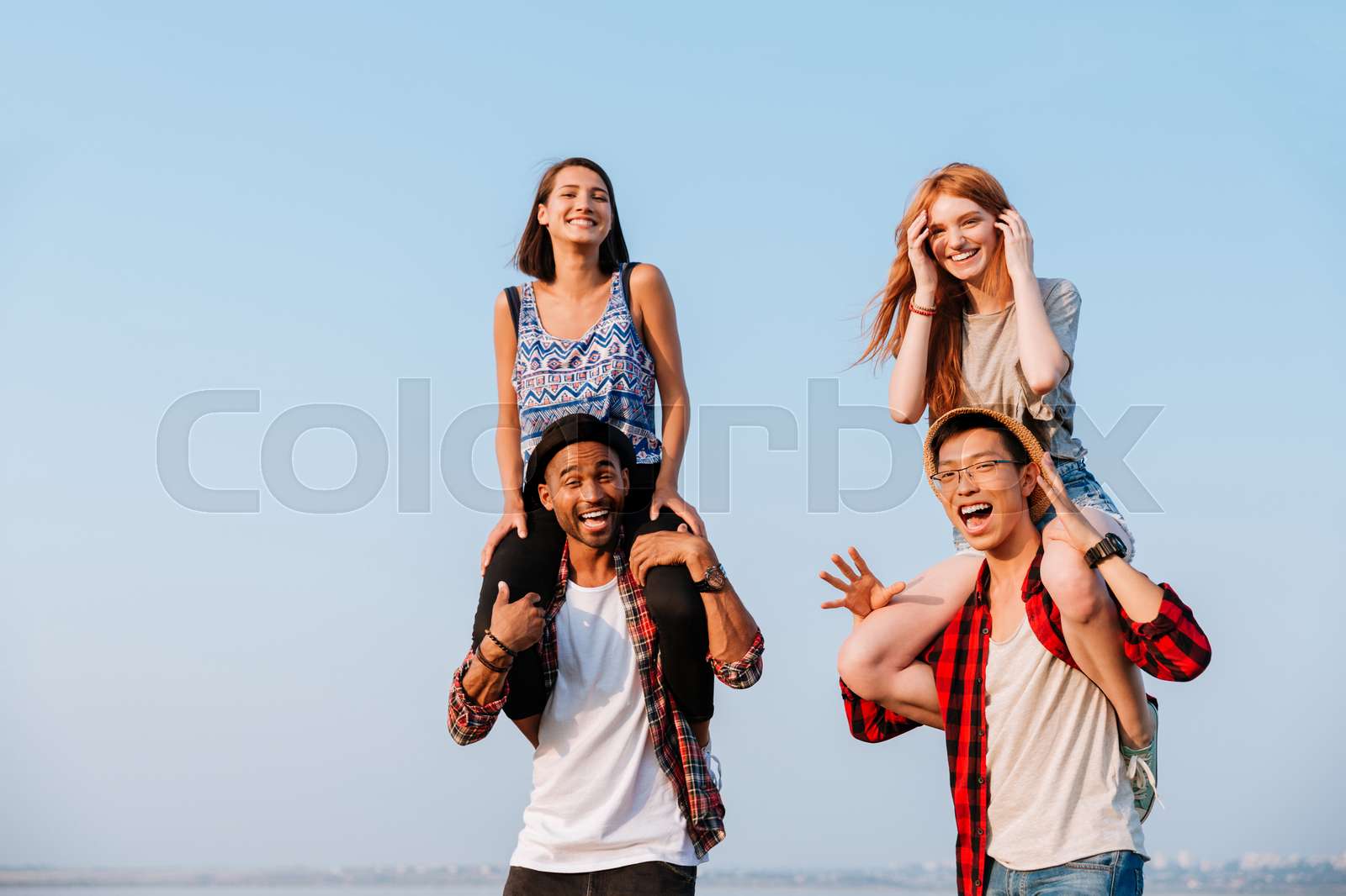 Two cheerful women sitting on shoulders of their boyfriends | Stock ...