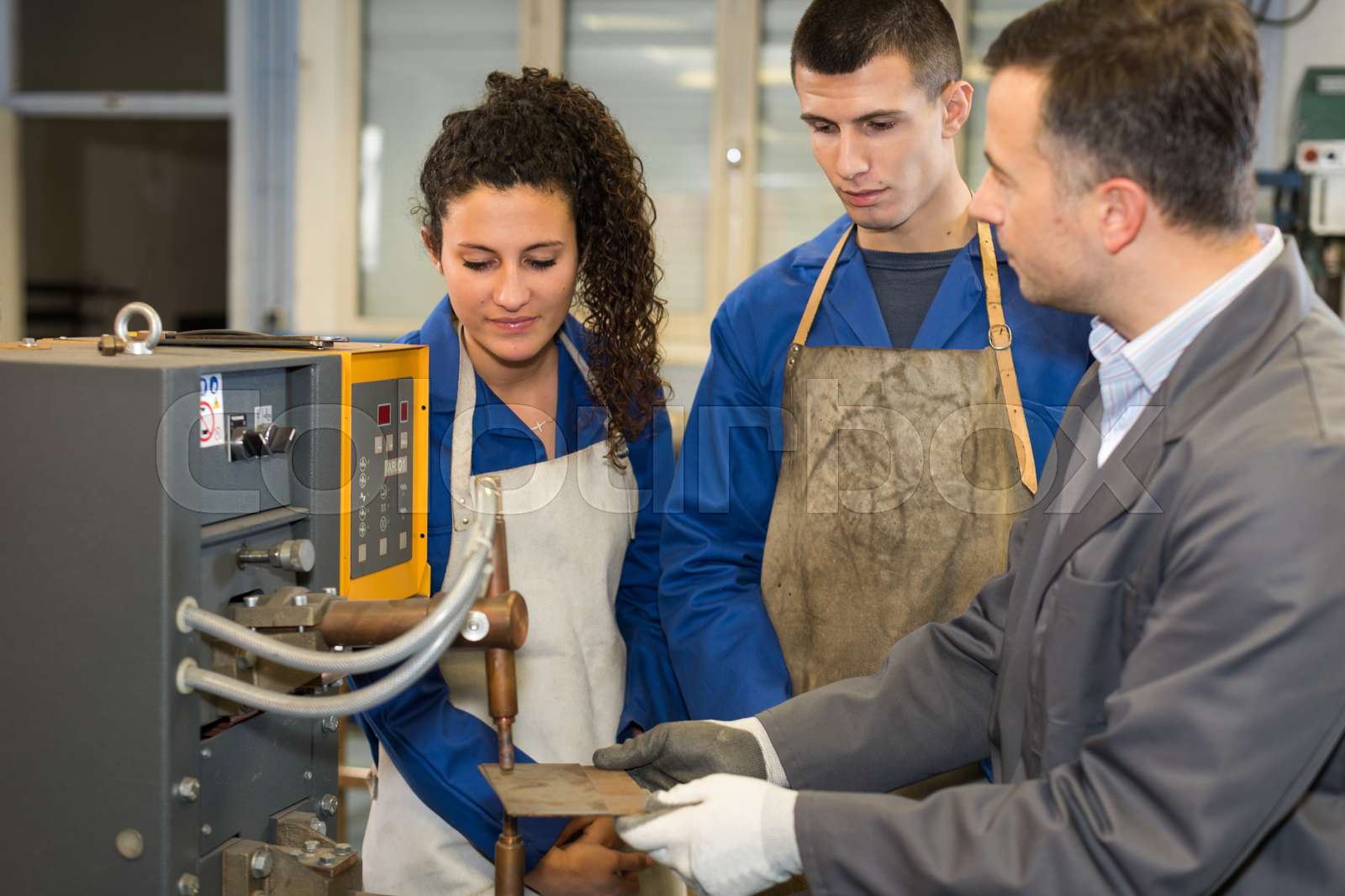 Students watching instructor use industrial machine | Stock image ...