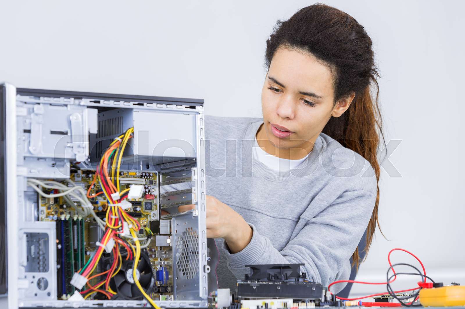 young woman attempting to repair a computer | Stock image | Colourbox