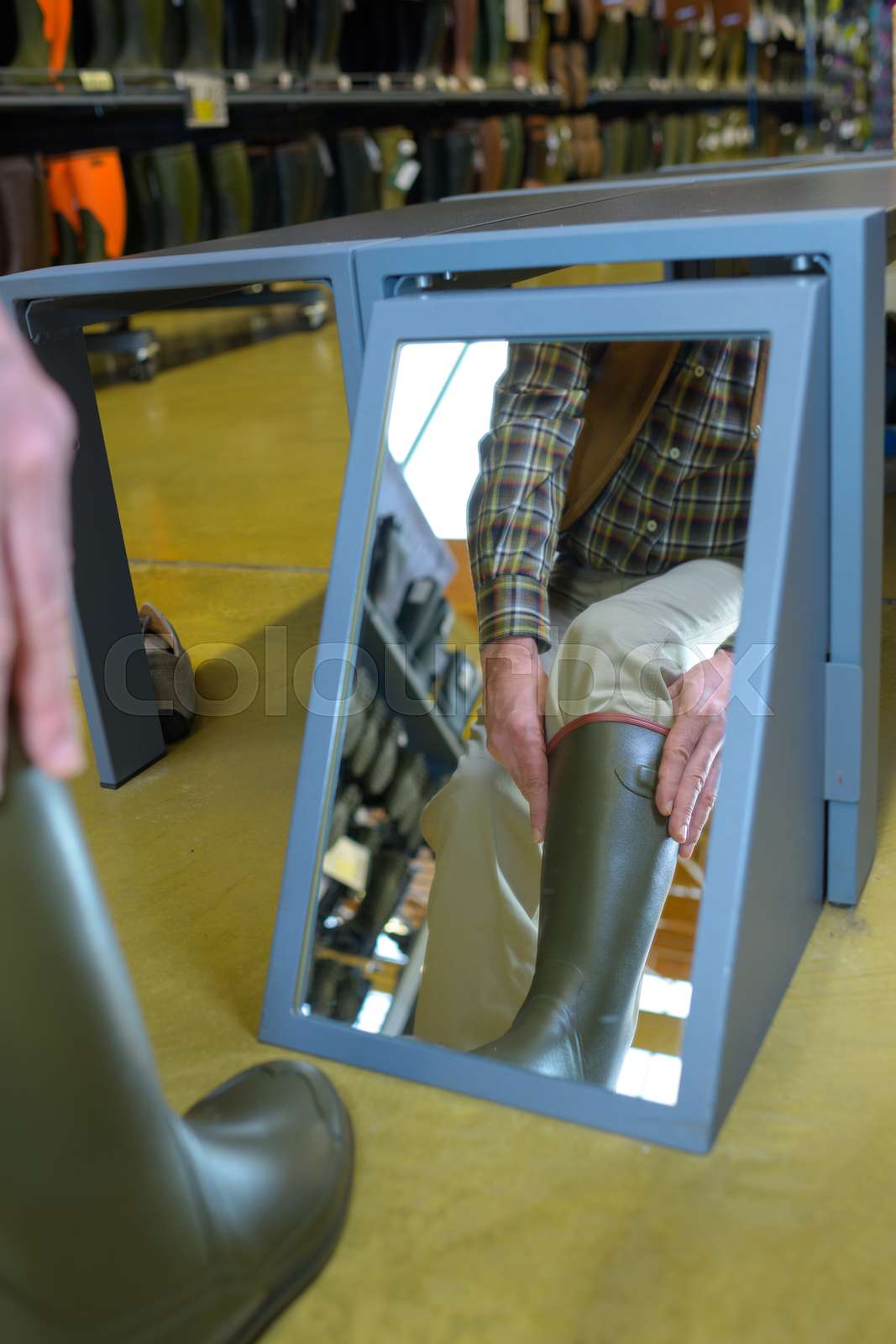 Man assessing boots in mirror | Stock image | Colourbox