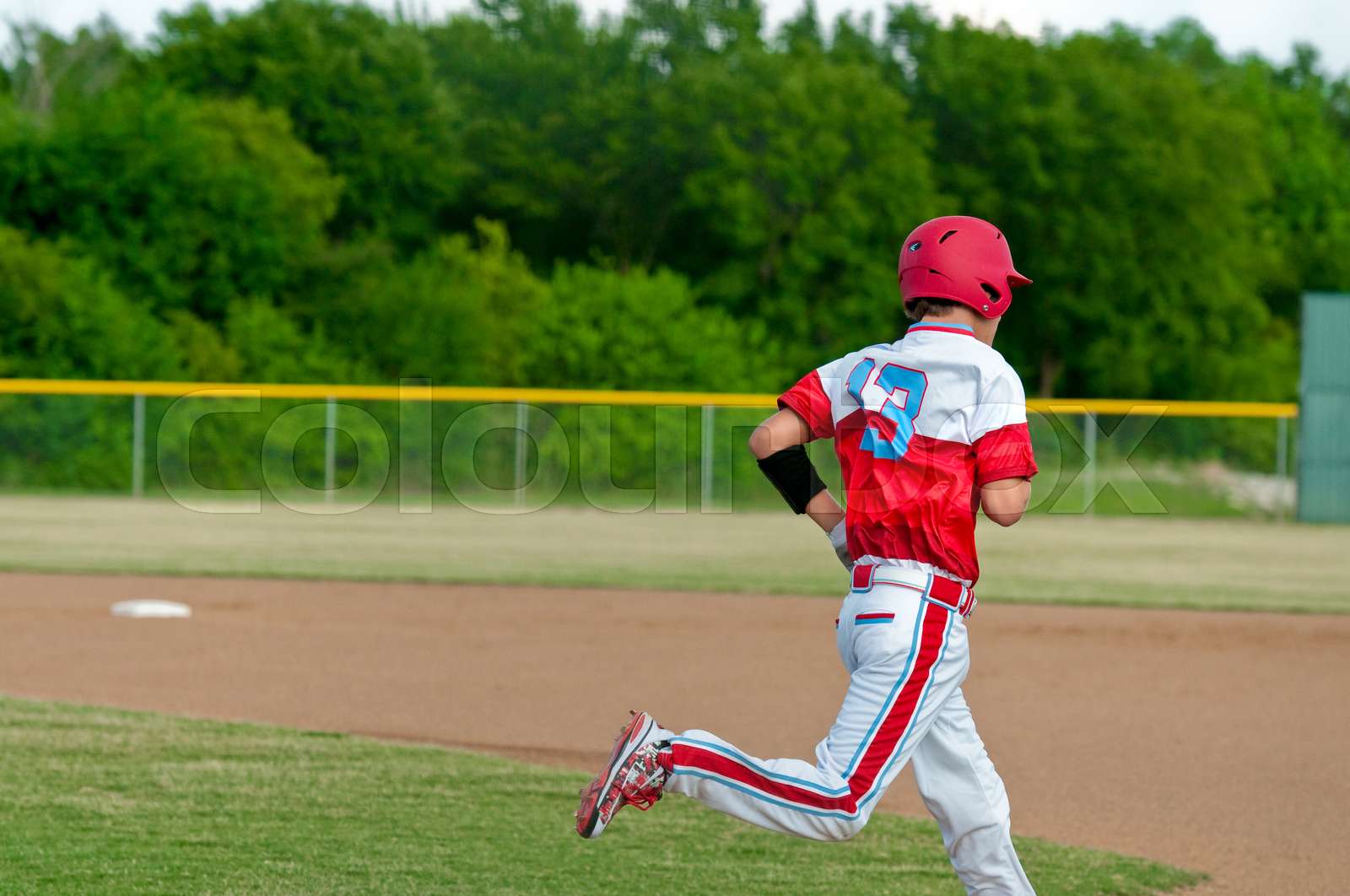 Teen baseball boy running to first base. | Stock image | Colourbox