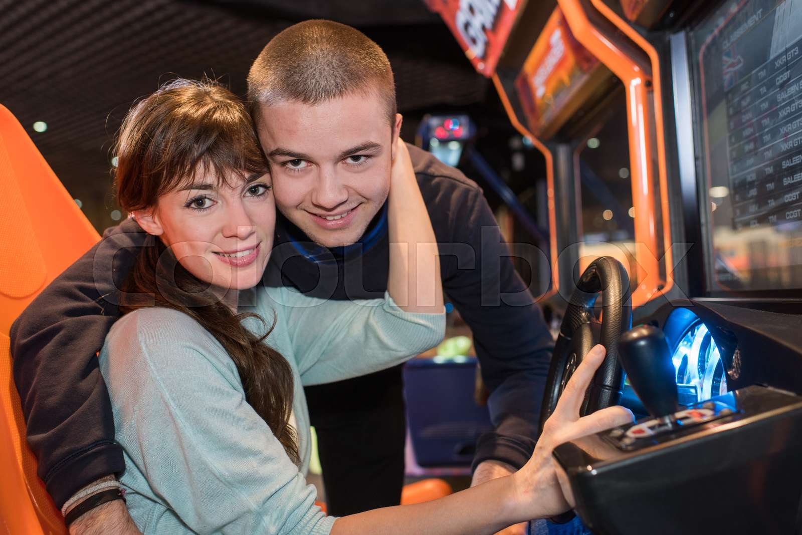 smiling boyfriend playing video games with girlfriend on amusement park ...