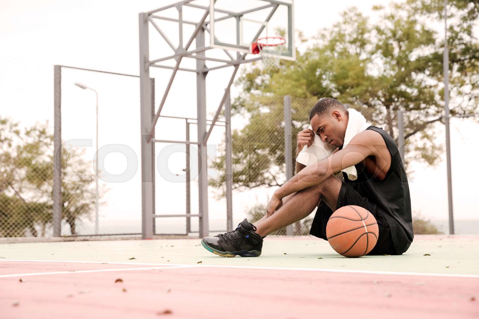 Tired basketball player sitting in the park with towel | Stock image ...