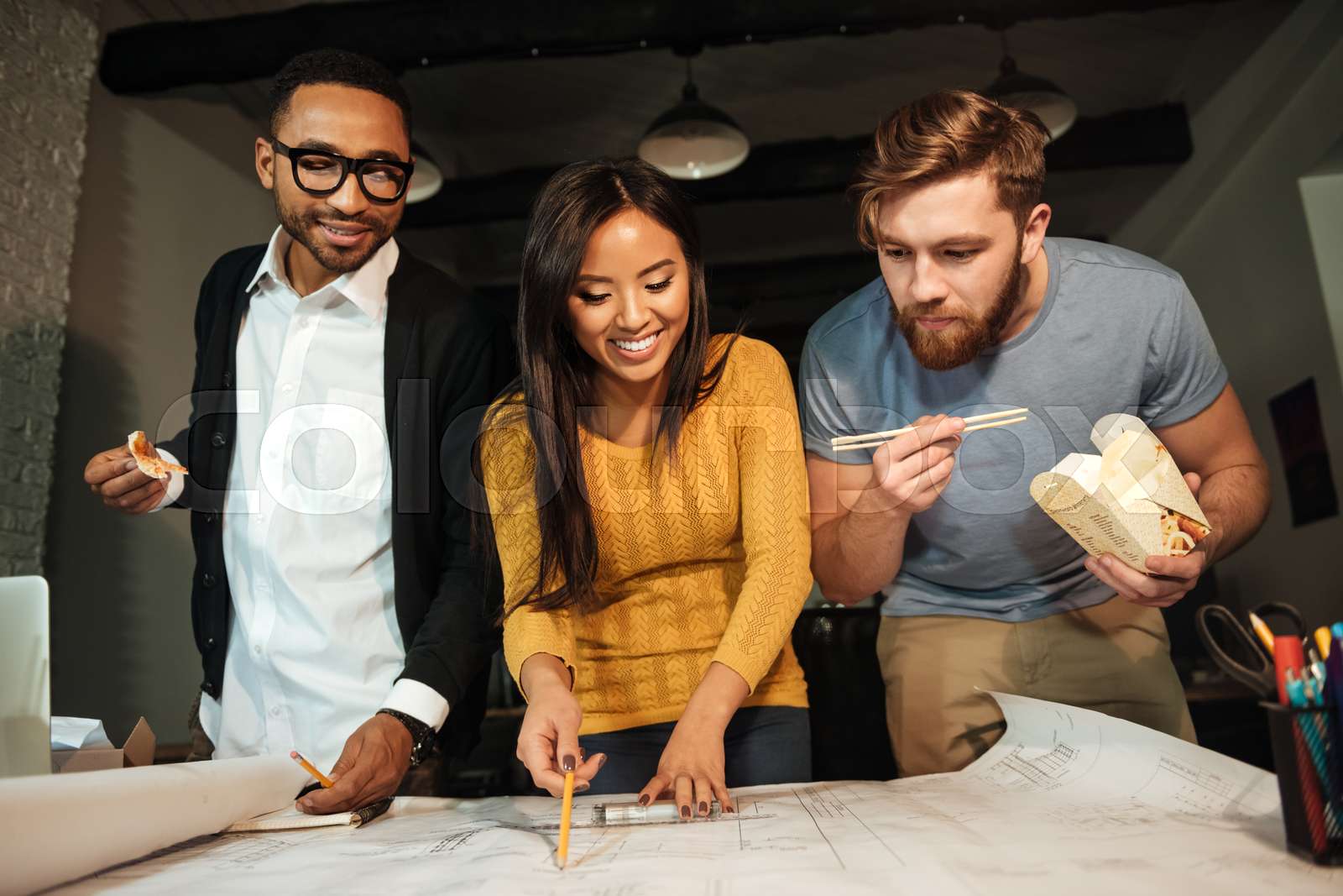 Happy architects working at night while looking on project | Stock image | Colourbox