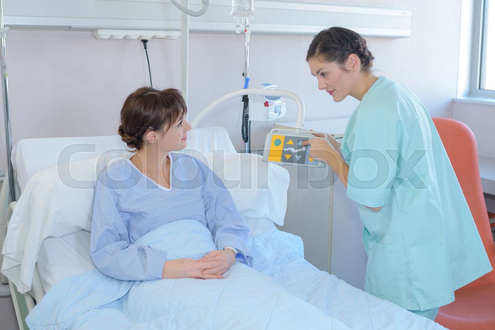 Nurse showing patient the hospital bed controls | Stock image | Colourbox
