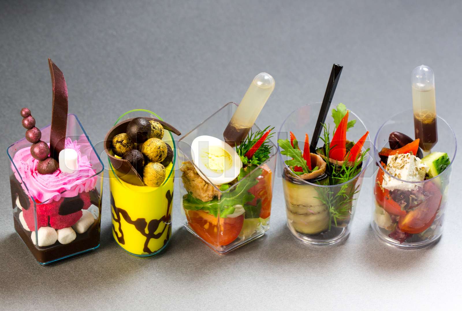 Mini desserts and meat canapes vegetable snacks in plastic cups canaps ...