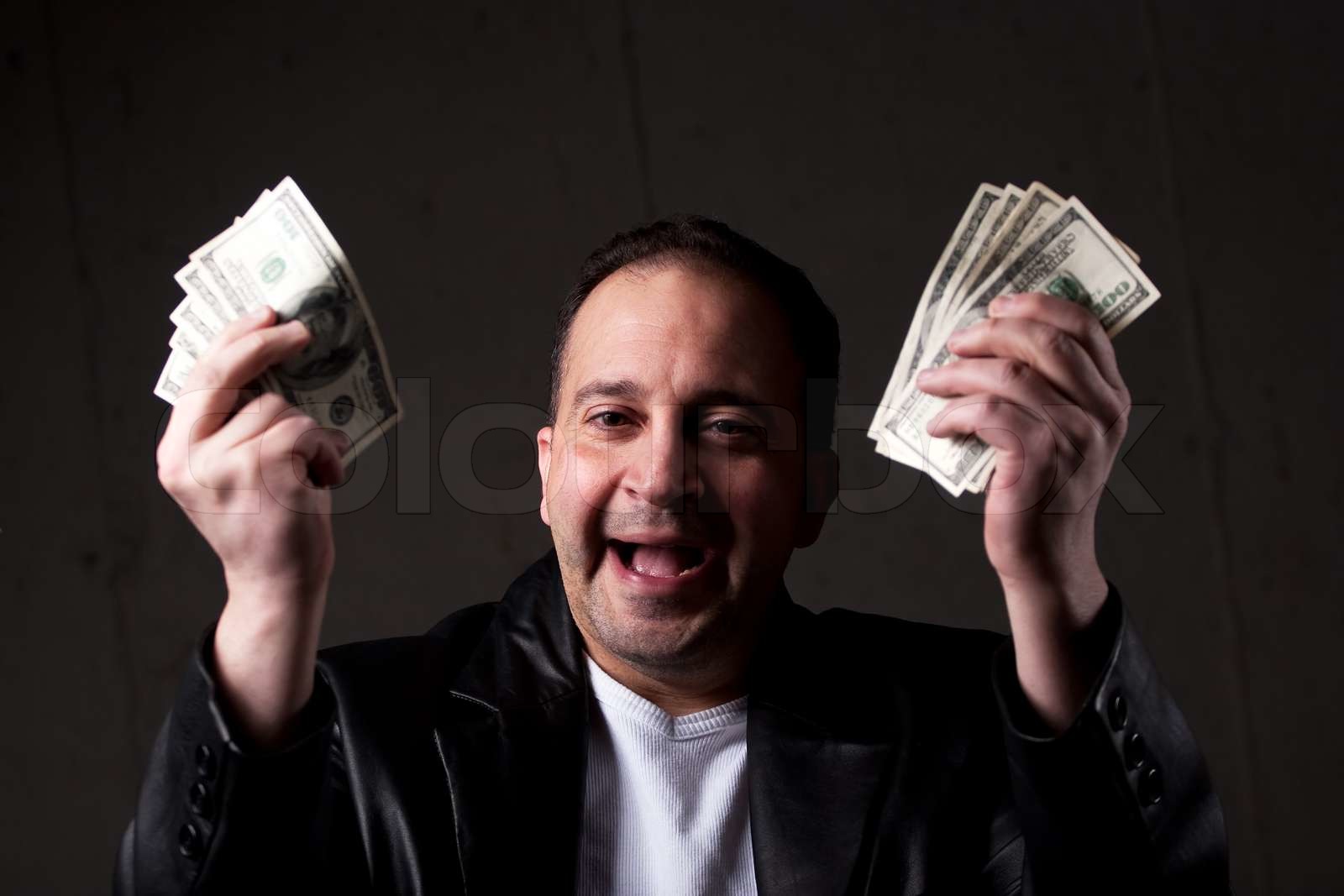 A man celebrating holding handfuls of green American cash money Shallow ...