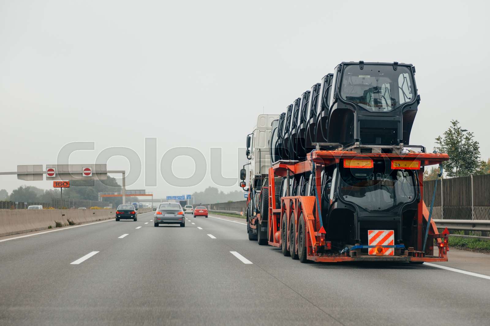 rear view of a big truck with flatbed trailer hauling tractor cabins ...