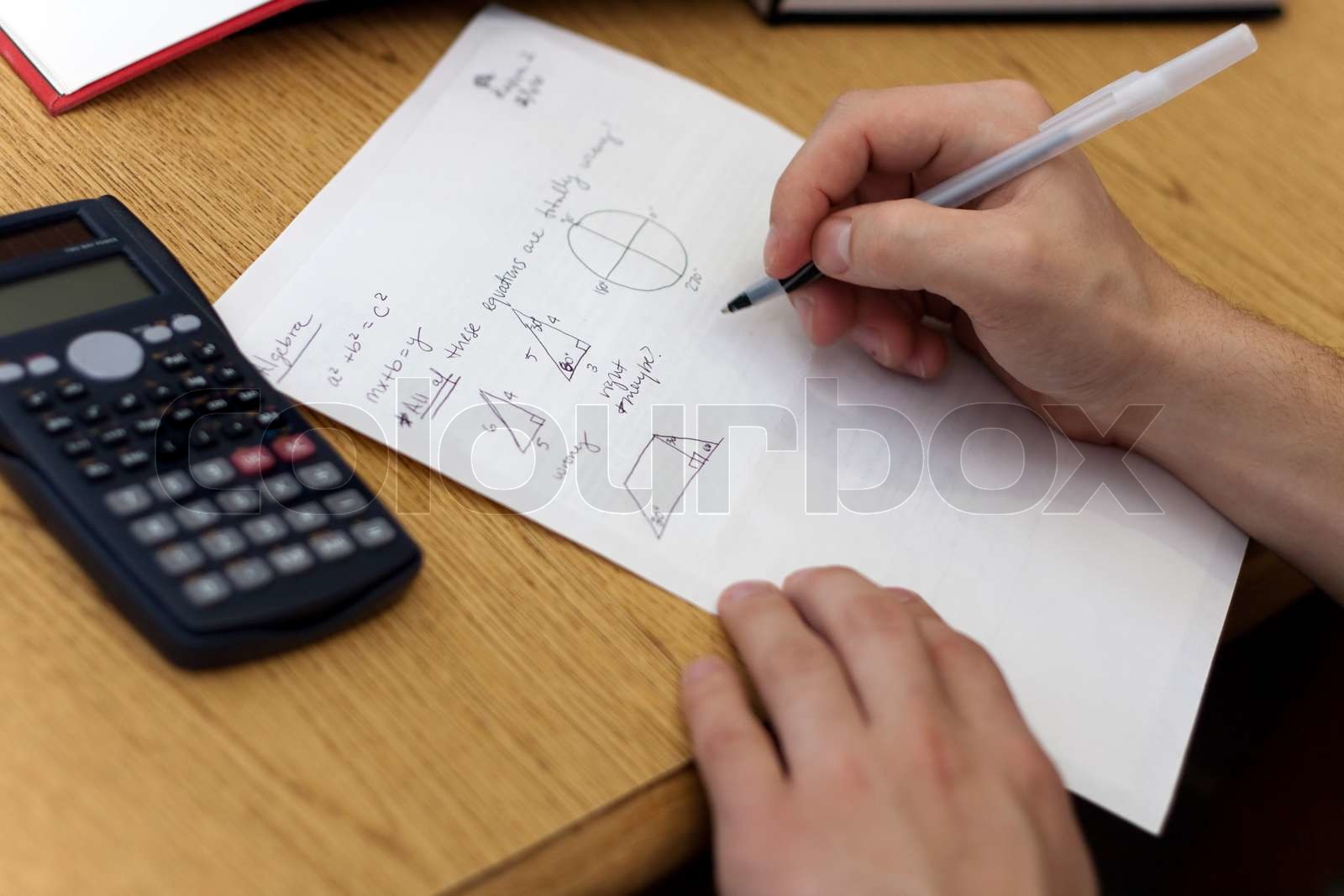 A young man working out mathematical equations on paper | Stock image ...