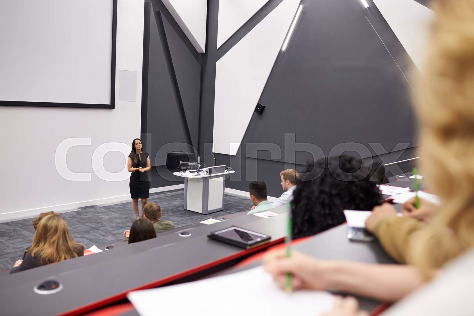 Woman lecturing students in a lecture theatre, mid row POV | Stock ...