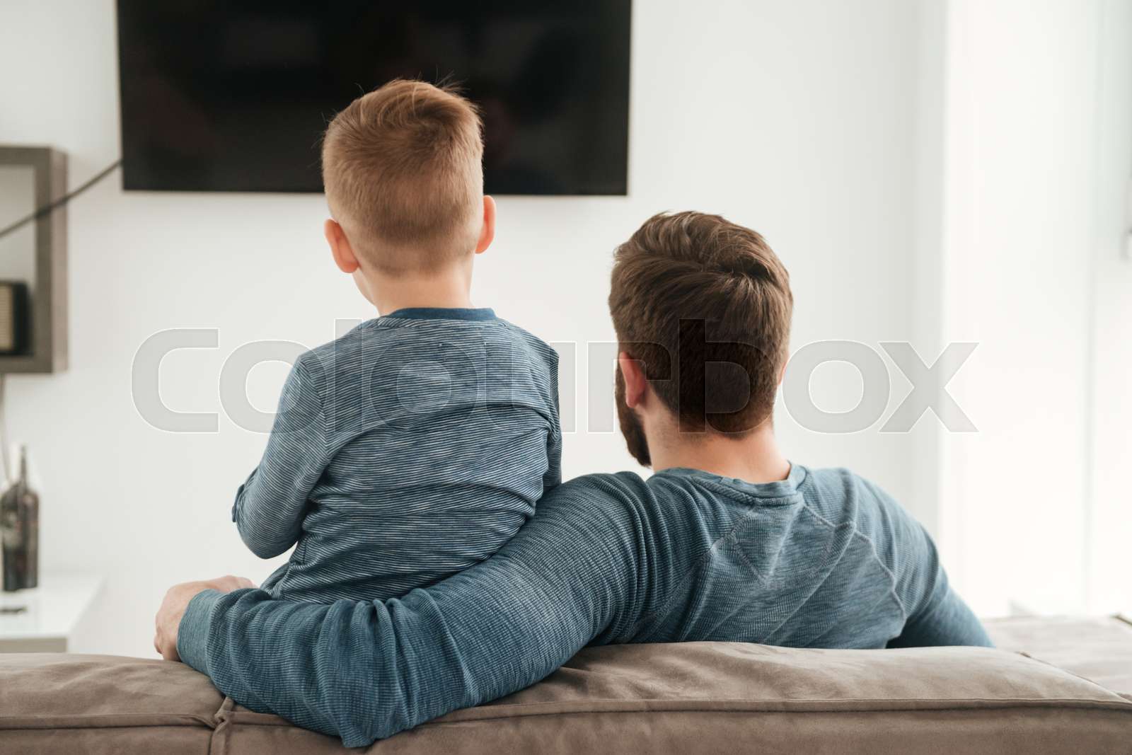 Back view photo of father watching TV with his son. | Stock image ...