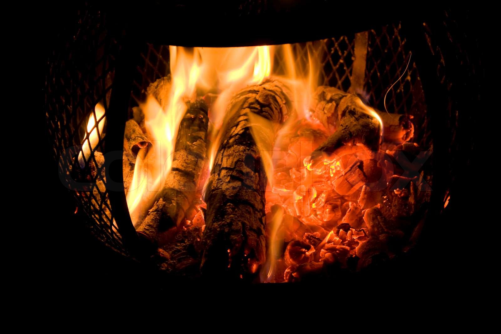 A red hot fire burning in a backyard chiminea with red glowing embers ...