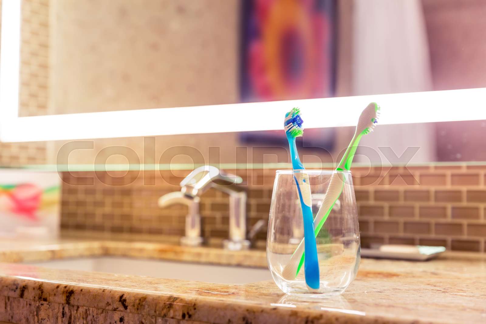 Toothbrushes in a glass on counter. | Stock image | Colourbox
