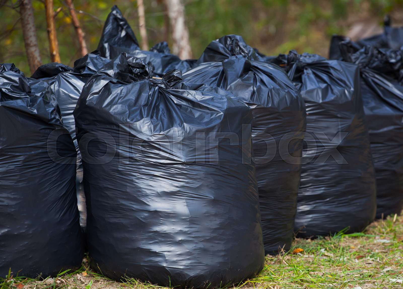 Black, complete and tied garbage bags standing together on the street ...