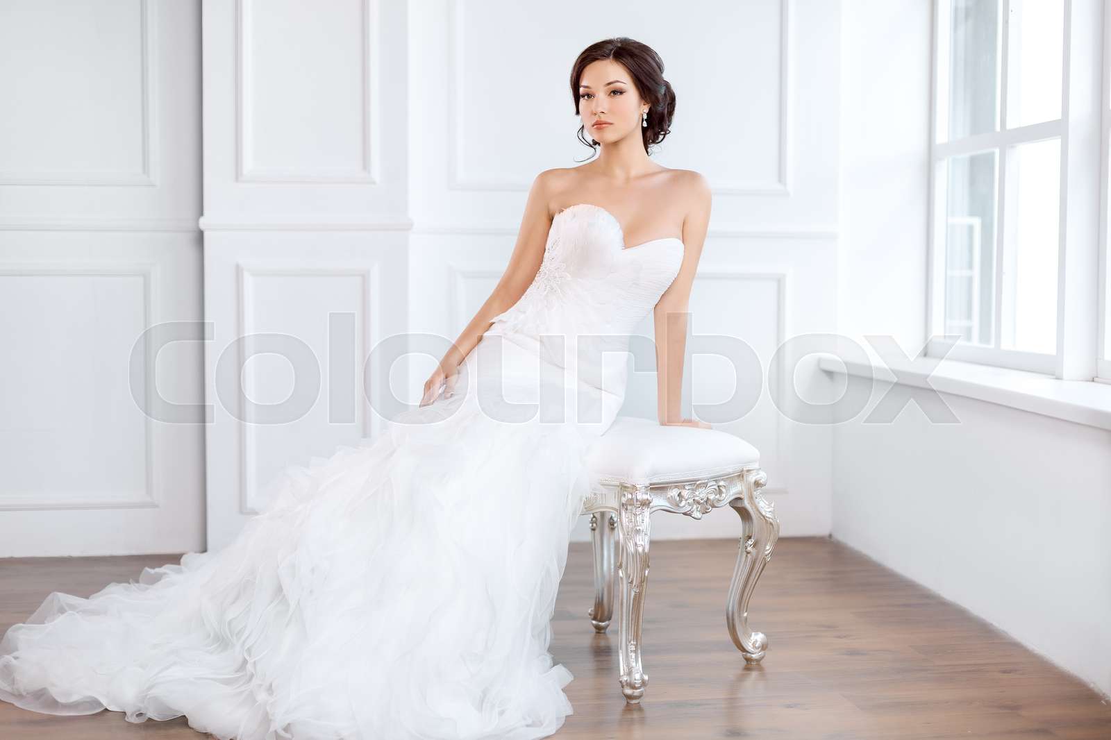 Bride in beautiful dress sitting on chair indoors | Stock image | Colourbox