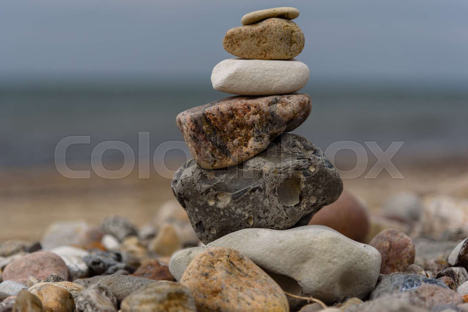 Sten i forskellige størrelser er stablet oven på hinanden på en strand ...